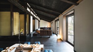 Um interior japonês tradicional com tatames, uma mesa de madeira baixa com tigelas e uma panela pendurada.