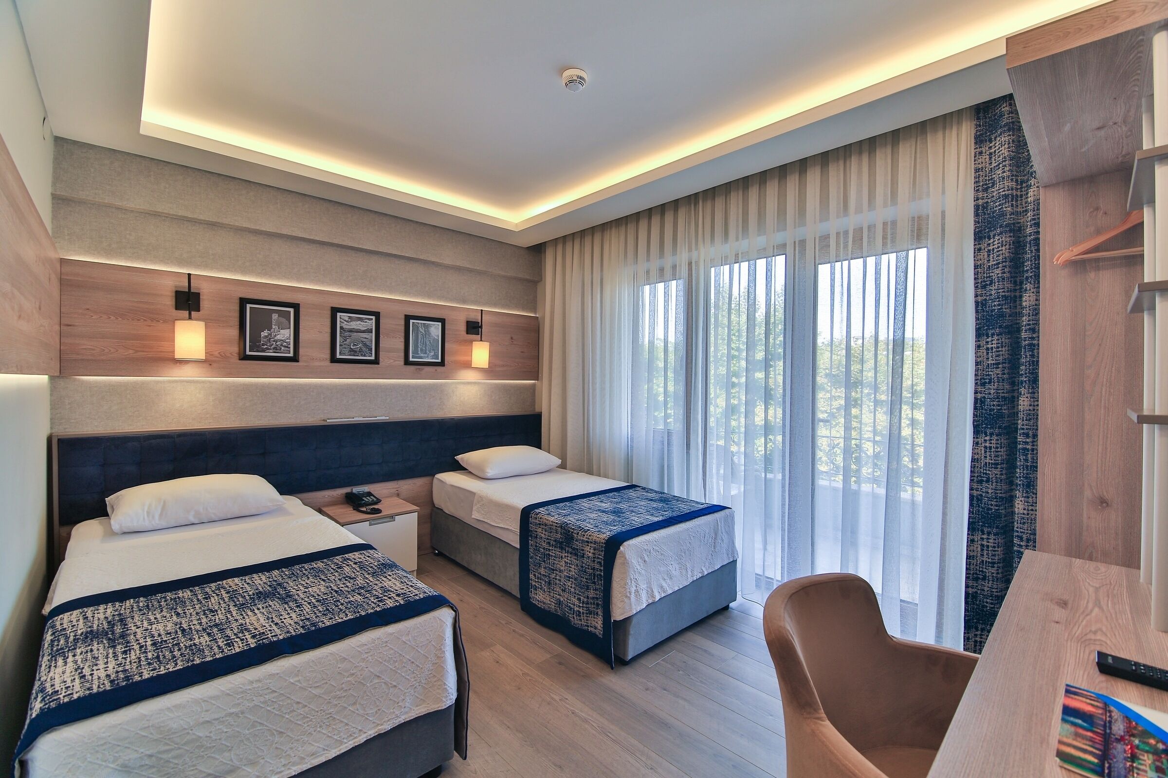 Quarto de hotel com duas camas, uma escrivaninha e uma cadeira.