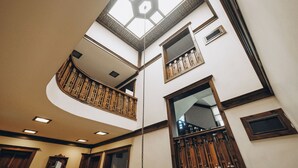 Interior com vários níveis, claraboia, corrimãos de madeira e corrente de segurança.