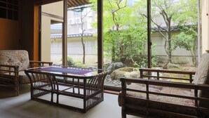 Um quarto japonês tradicional com tatames, uma mesa baixa com um tapete roxo e dois assentos de tatame.
