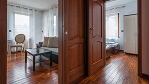 Quarto de hotel com piso de madeira, um sofá, uma mesa e um guarda-roupa.