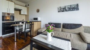Cozinha moderna com área de refeições, um sofá e uma mesa de centro com um vaso de flores.