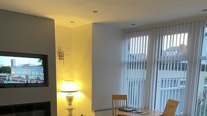 Uma sala de estar moderna com lareira, área de refeições e grandes janelas.