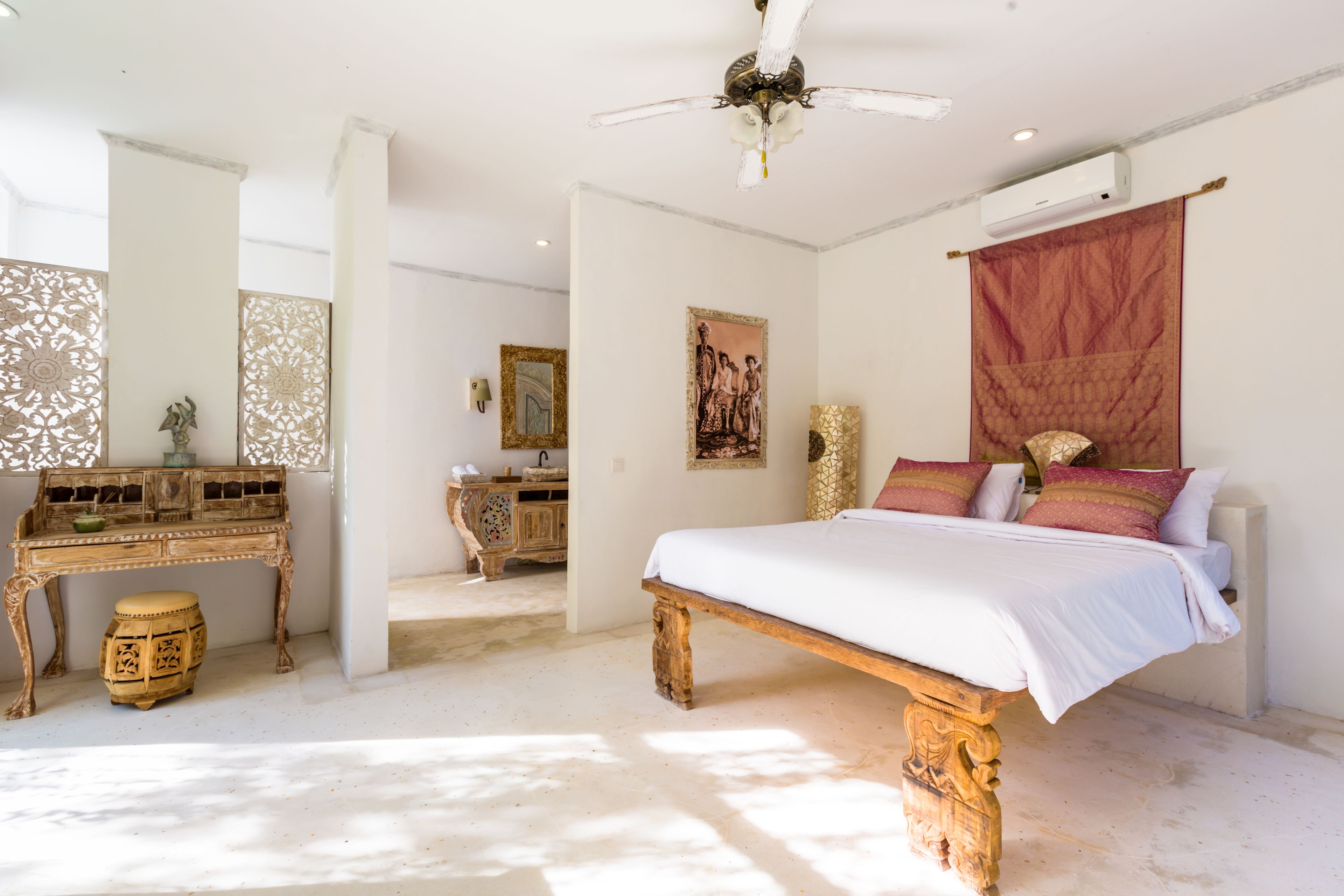 Quarto com cama grande, escrivaninha de madeira e painel decorativo na parede.
