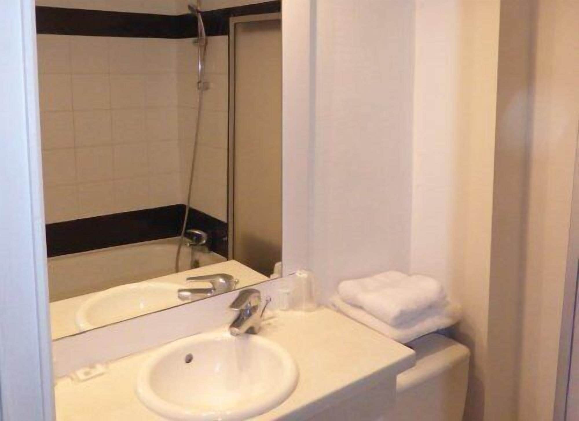 Casa de banho com lavatório, espelho e chuveiro.