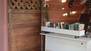 Uma escrivaninha branca com uma estante, uma porta de madeira e uma pequena planta.