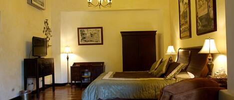 Quarto de hotel com uma cama, uma cadeira, uma televisão e obras de arte nas paredes.