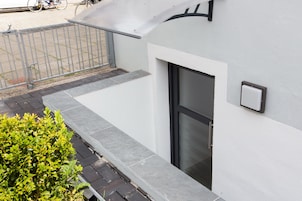 Um edifício moderno com guarda-corpo de metal, uma porta e uma pequena janela.
