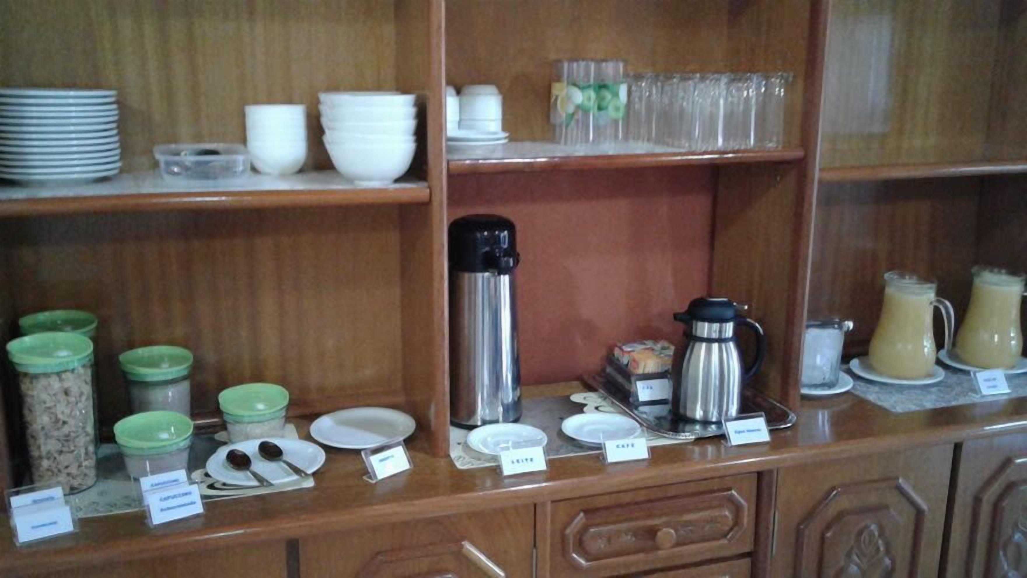 Disposição de buffet de café da manhã com diversos alimentos e utensílios.