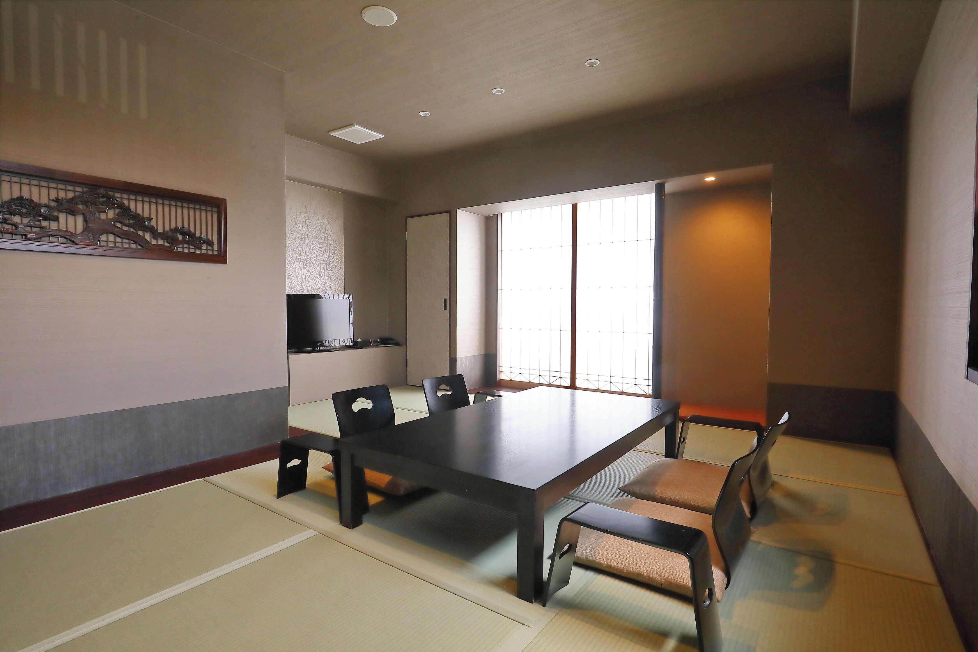 Um quarto em estilo japonês tradicional, com tatames, uma mesa baixa e cadeiras.
