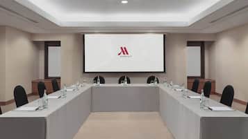 Sala de conferência com uma mesa comprida, cadeiras e uma tela exibindo o logotipo da Marriott.
