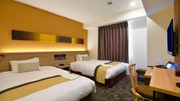 Quarto de hotel com duas camas, uma escrivaninha, uma cadeira e uma televisão.