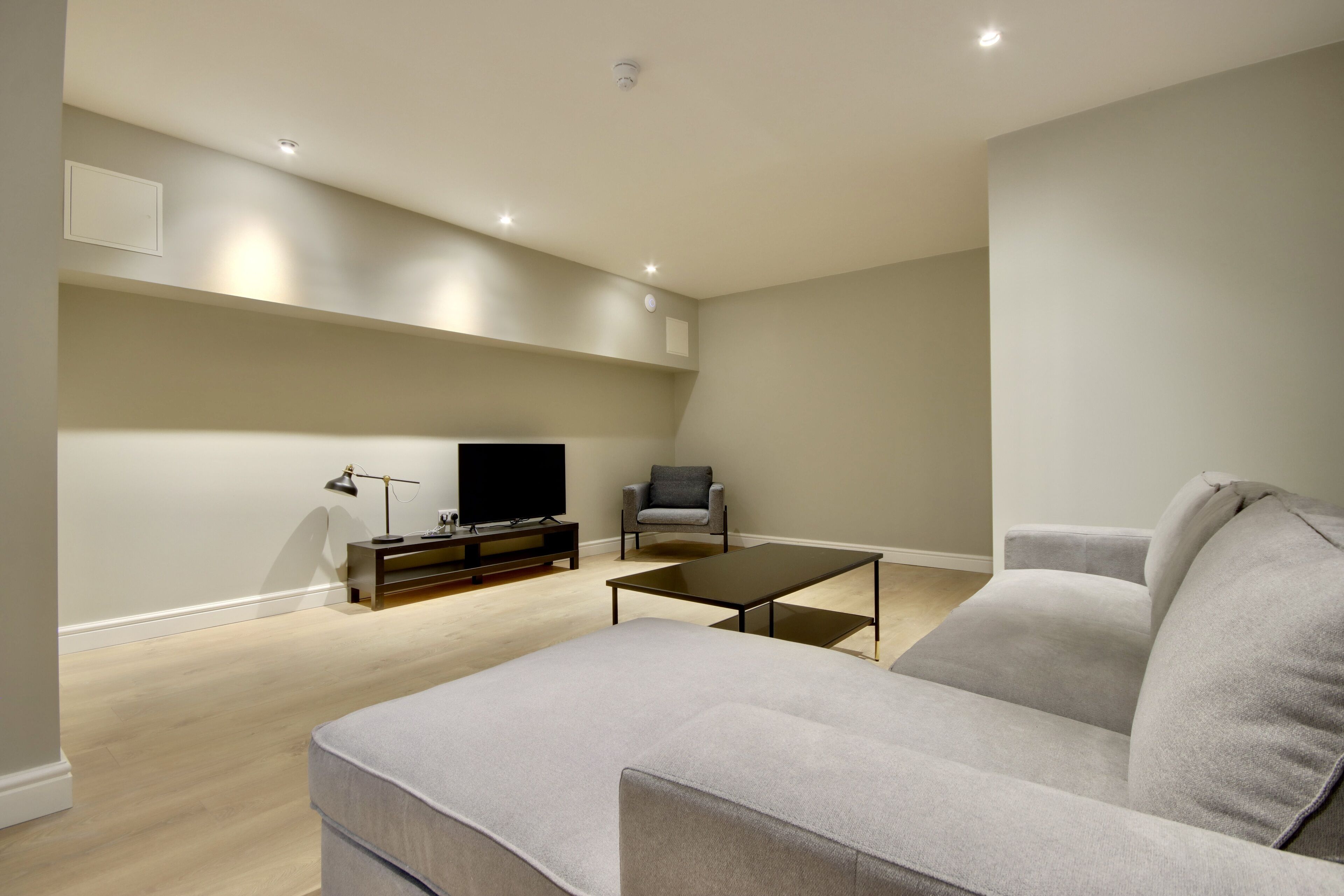 Uma sala de estar moderna com um sofá, uma mesa de centro, uma TV em um suporte e uma poltrona.