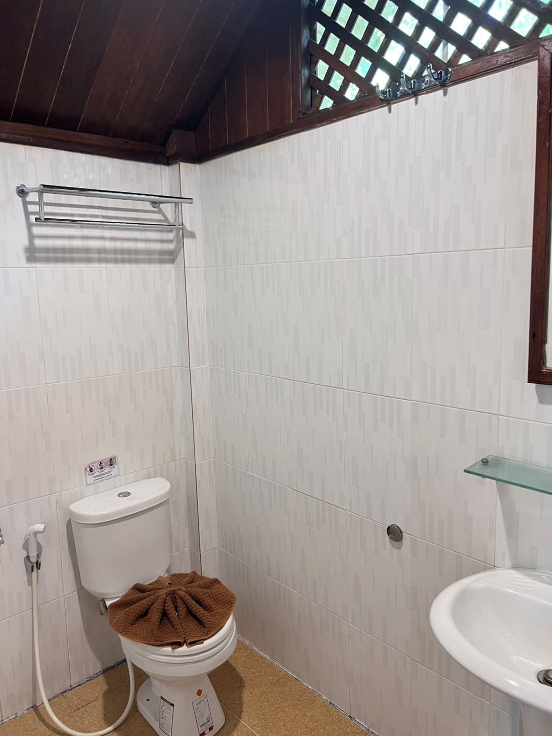 Casa de banho com sanita, lavatório e porta-toalhas.