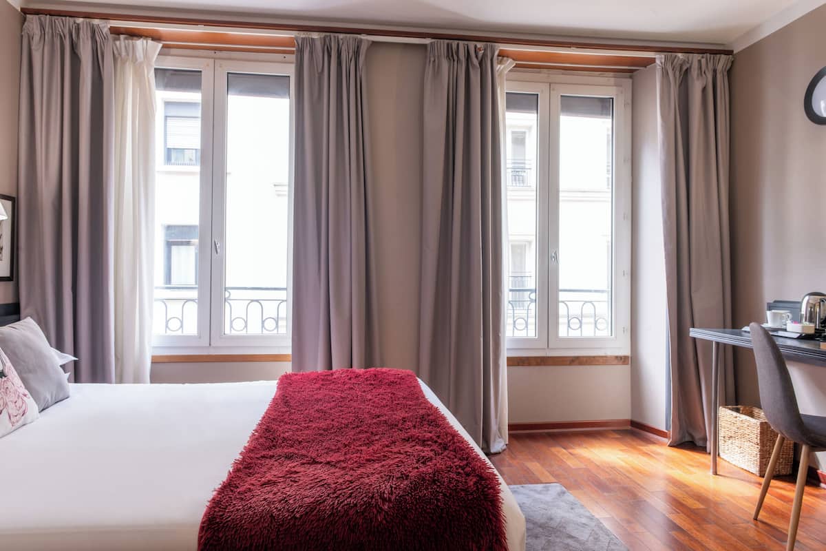 Quarto de hotel com uma cama, uma mesa e vista para a varanda externa.