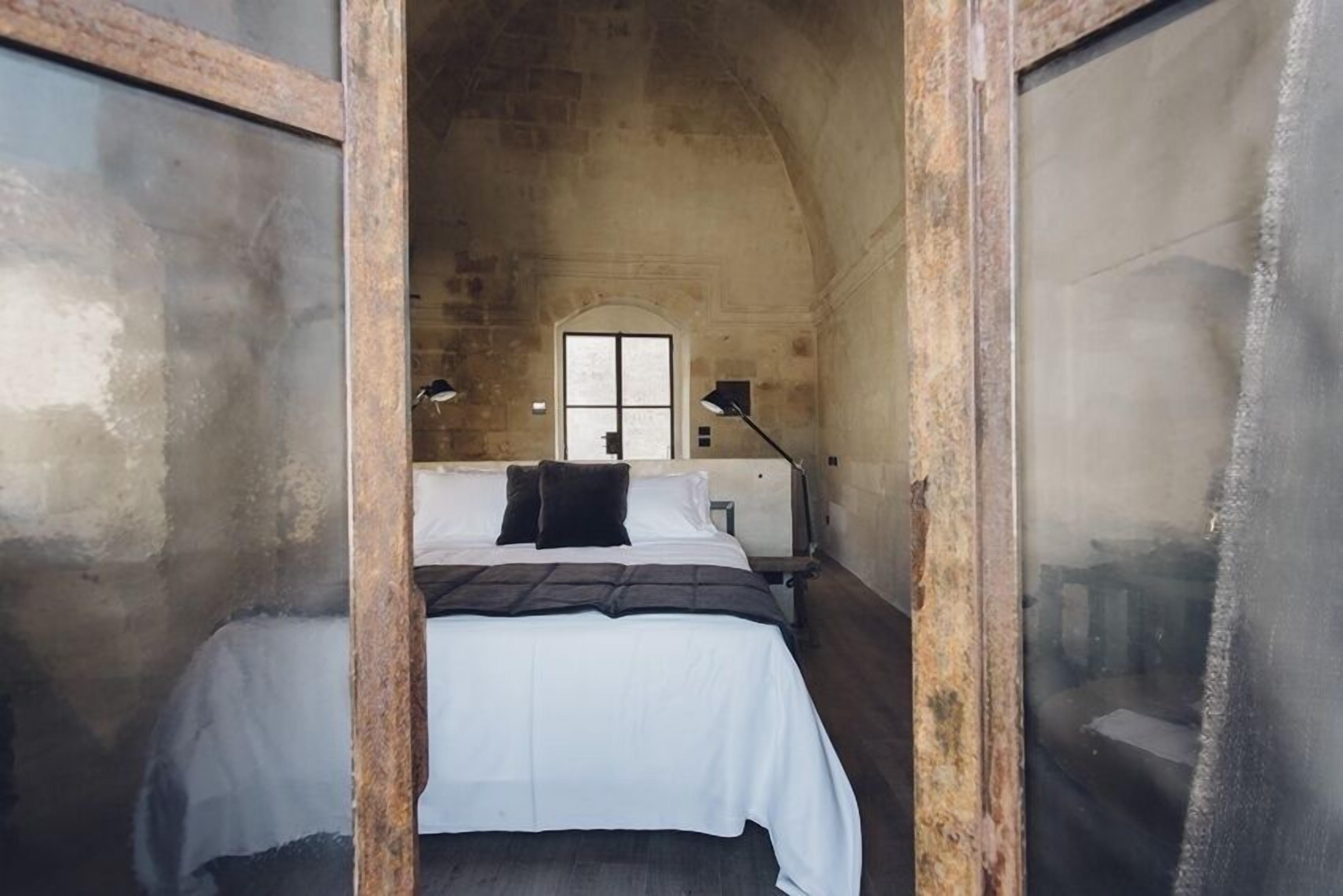 Um quarto com uma cama, janela e luminária.