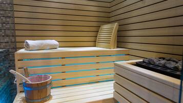 Uma sauna de madeira com um banco, um balde e um relógio fixado na parede.