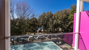 Uma varanda com vista para carros estacionados e árvores.