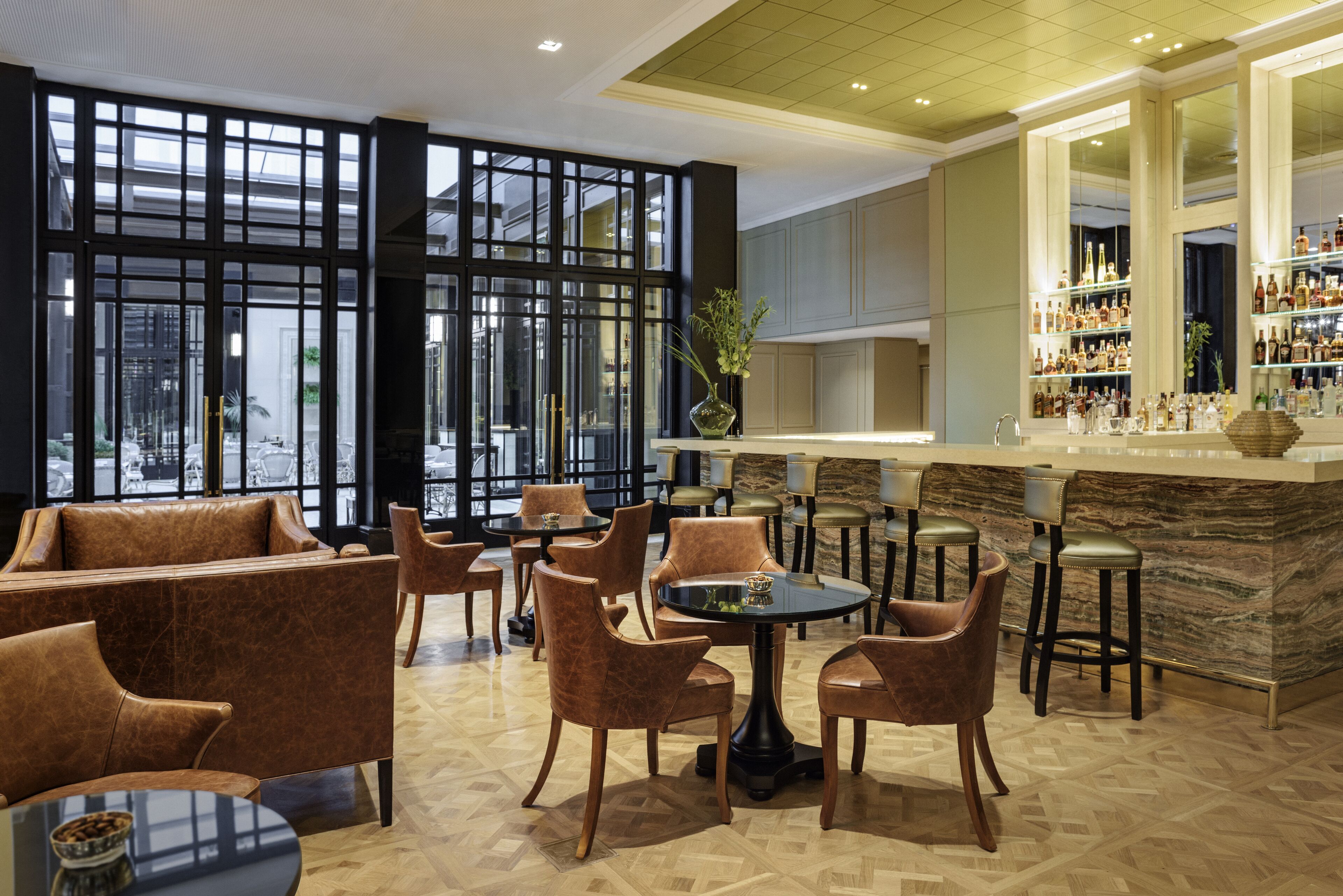 Uma área de bar moderna com assentos de couro, balcão de mármore e vista pela ampla janela.