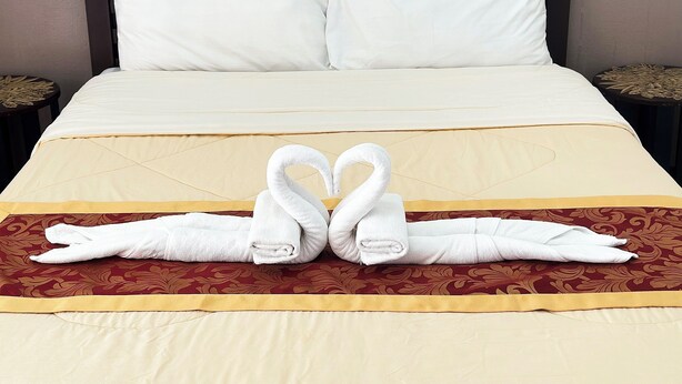 Cama bem arrumada com almofadas brancas e uma toalha decorativa.