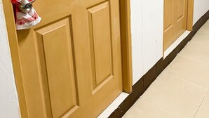 Um corredor com portas de madeira, uma delas com um pequeno objeto decorativo na maçaneta.