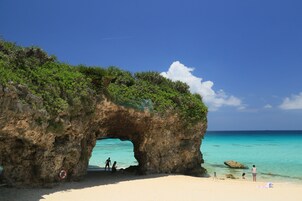 Formação rochosa natural em arco numa praia com águas turquesa cristalinas.