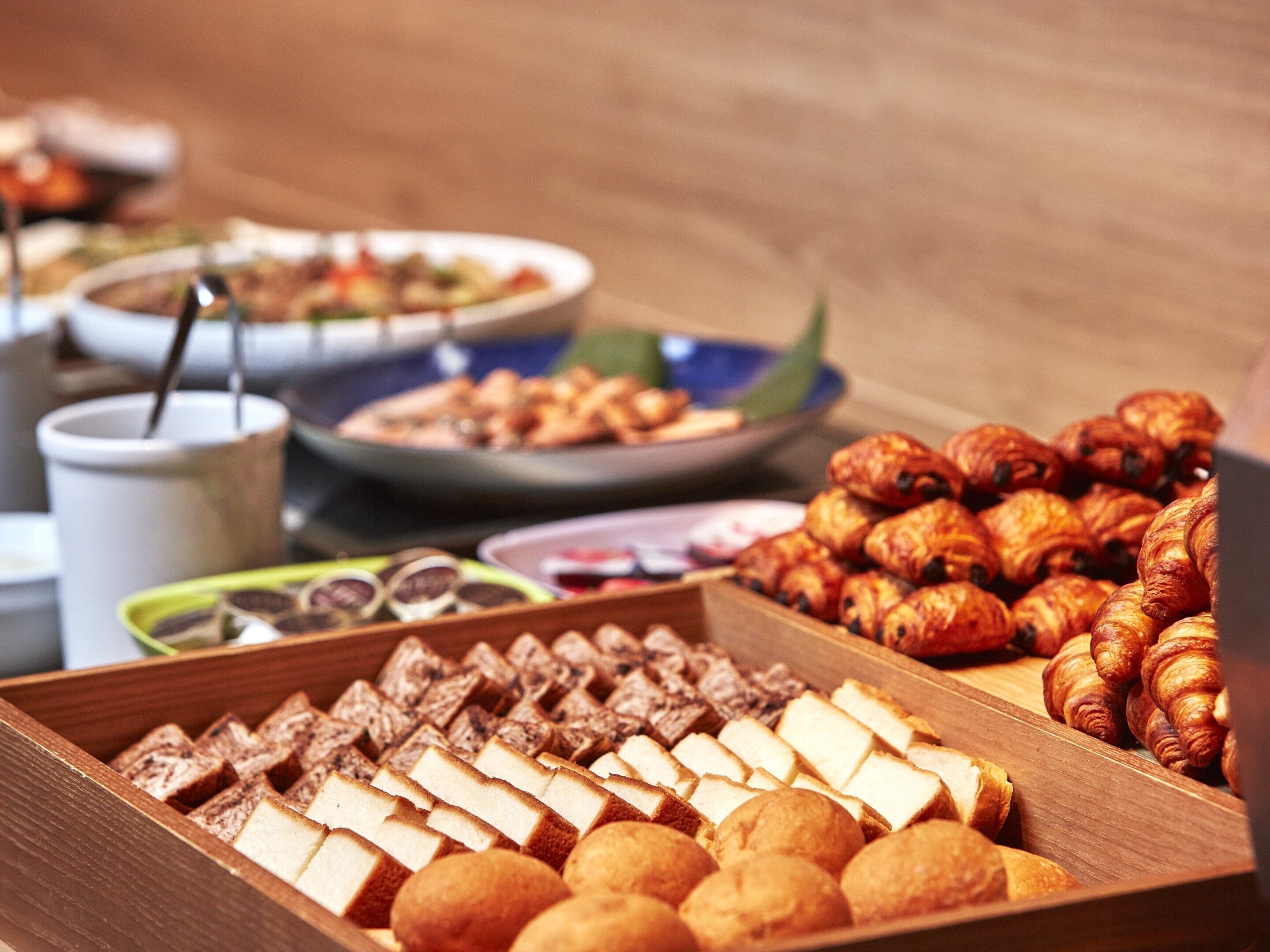 Buffet com diversos alimentos, incluindo pão, doces e uma variedade de pratos.