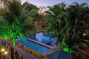 Uma piscina cercada por plantas tropicais e rochas, com vista para o céu.