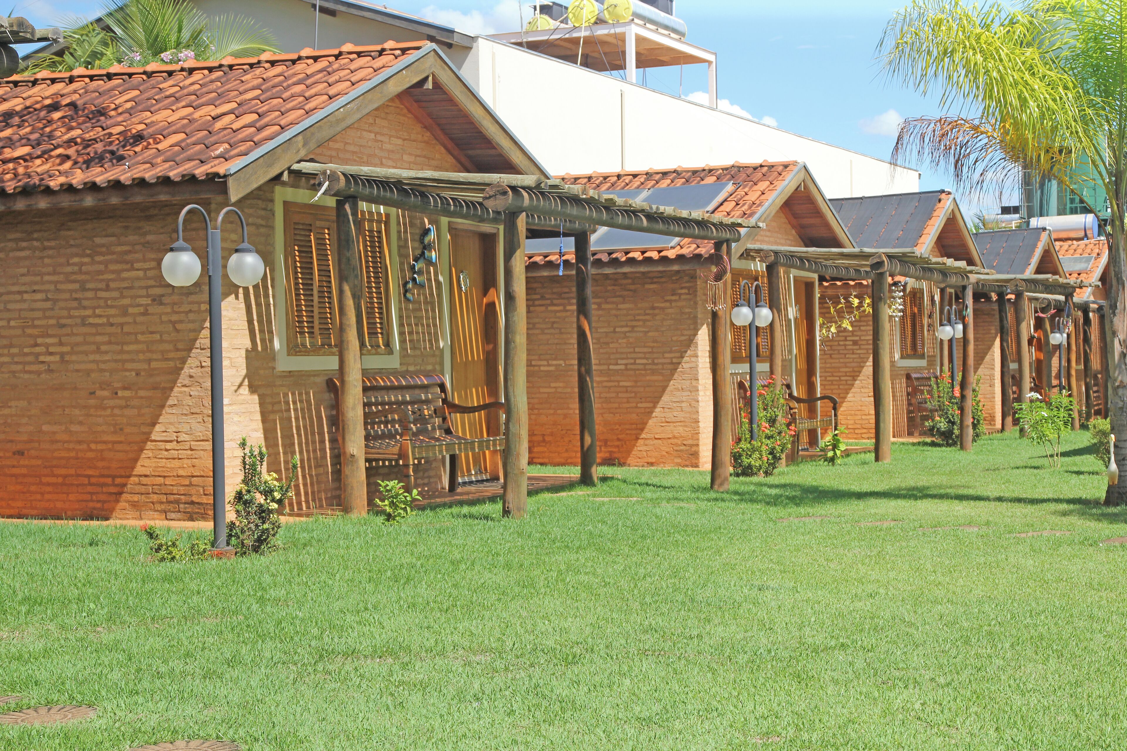 Fileira de casas de tijolo com telhados de cerâmica, varandas de madeira e luminárias suspensas.