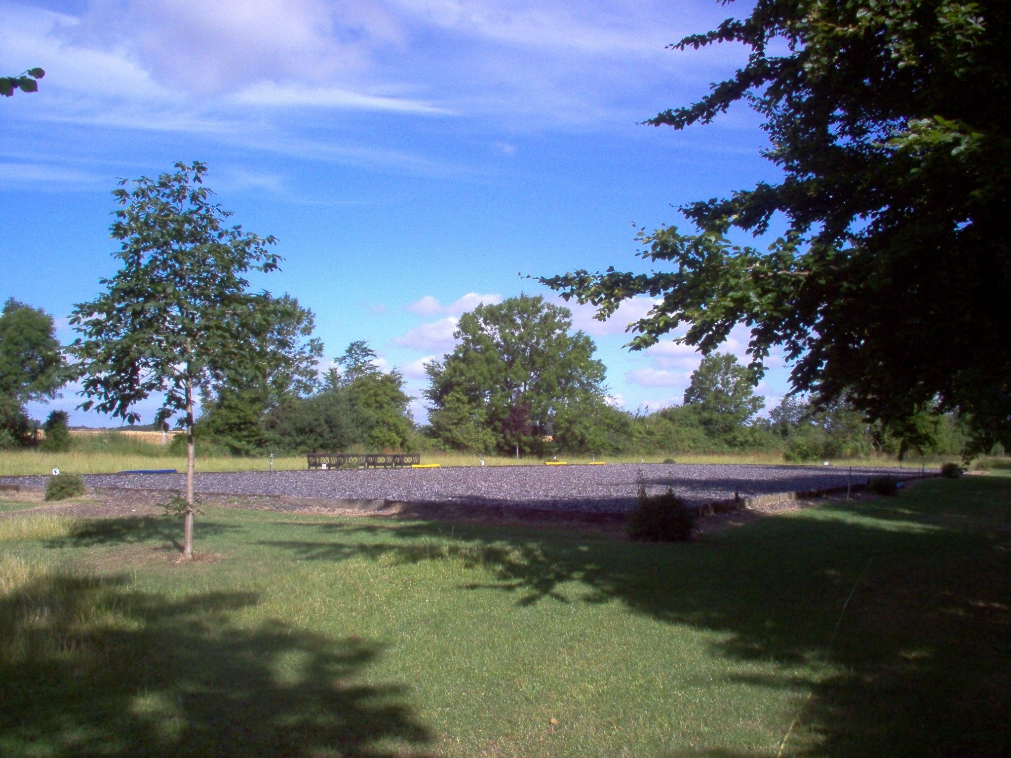 Um campo gramado com árvores e um caminho de cascalho.