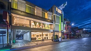 Um hotel com entrada no andar térreo, varandas nos andares superiores e um letreiro de neon.
