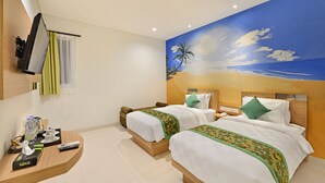 Quarto de hotel com duas camas, uma TV, uma mesa de trabalho e um mural com uma cena de praia.