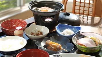 Uma refeição tradicional japonesa com diversos pratos dispostos numa bandeja, incluindo uma panela, tigelas de arroz e outros alimentos.