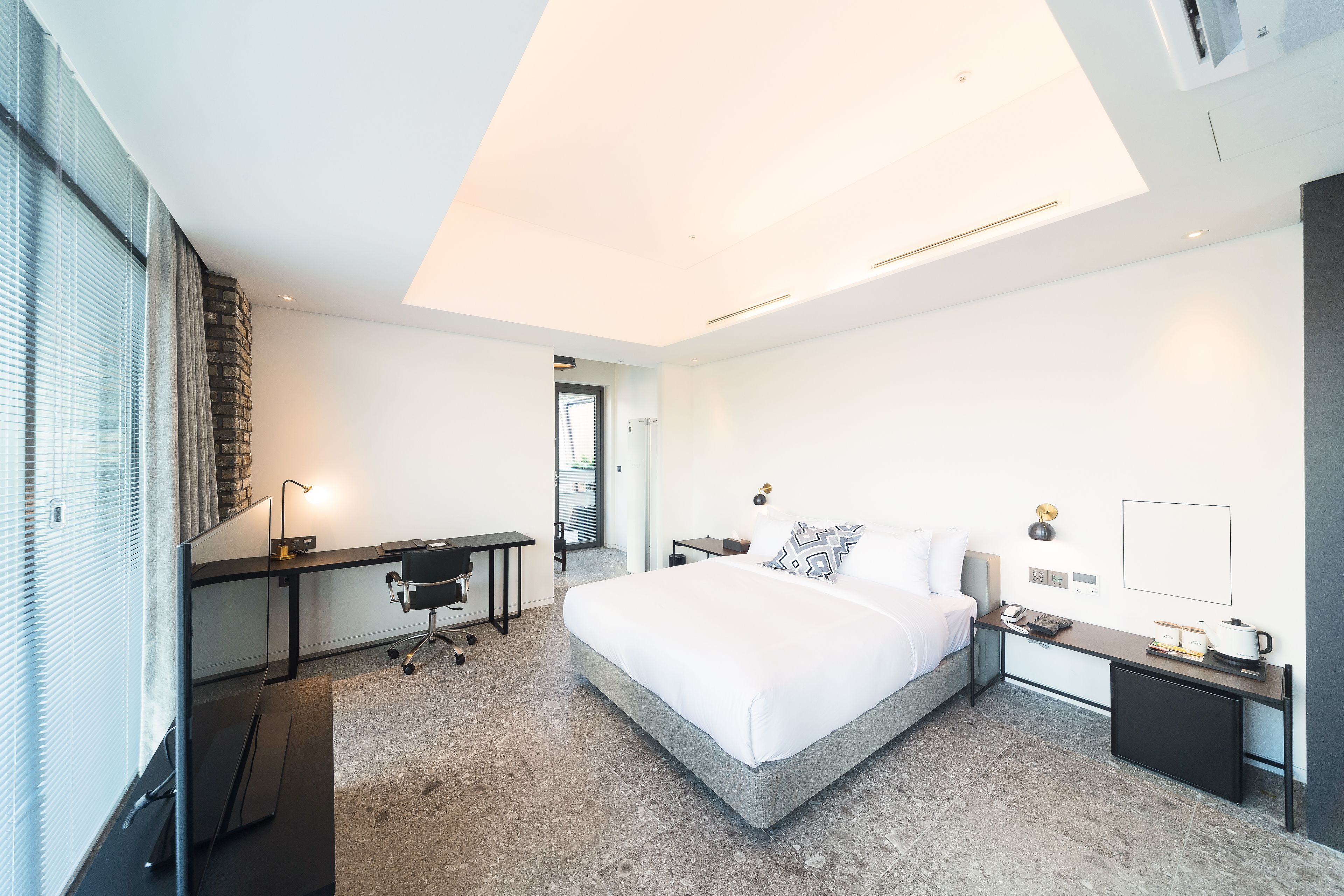 Quarto de hotel moderno com uma cama grande, uma escrivaninha e uma cadeira.