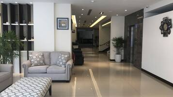 Um hall moderno com um sofá, um banco e uma planta em vaso.