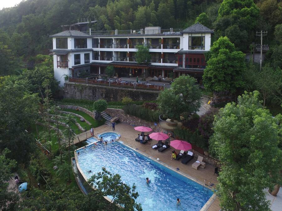 Um hotel com piscina, rodeado por vegetação exuberante e arquitetura tradicional.