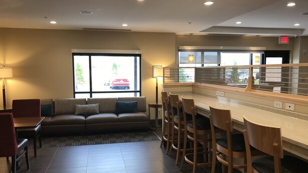 Um lobby moderno de hotel com área de estar, um bar e vista para o exterior.