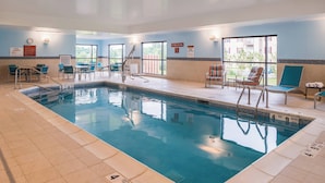 Piscina interior com marcações claras de profundidade, espreguiçadeiras e placa de 'Proibido Mergulhar'.