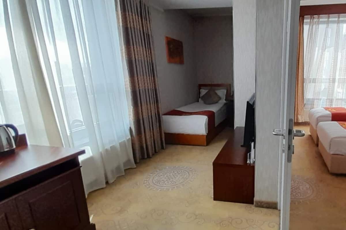 Quarto de hotel com uma cama, uma escrivaninha e uma televisão.