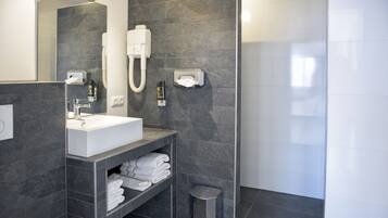 Casa de banho moderna com lavatório branco, porta-toalhas e dispensador de toalhas aquecido.