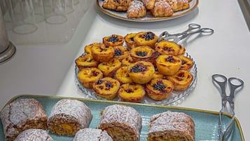Uma mesa de buffet com diversos doces e sobremesas, incluindo tartes e pastéis, dispostos em pratos e bandejas.