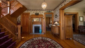 Uma sala de estar ampla com escada de madeira, lareira e tapete estampado.