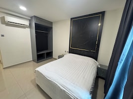Quarto com cama, guarda-roupa, unidade de ar condicionado e cabeceira com padrão marmorizado.