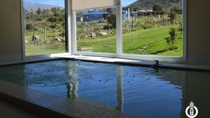 Piscina interna com vista para uma paisagem gramada e edifícios ao fundo.