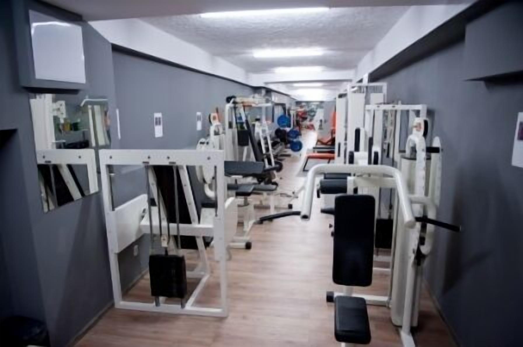 Uma academia com diversos aparelhos e equipamentos de ginástica.