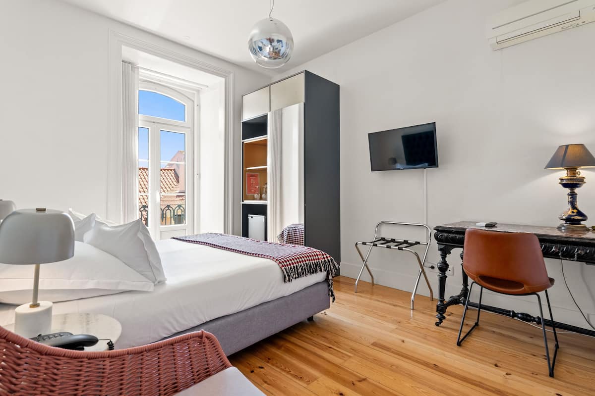 Quarto moderno com cama, mesa de cabeceira, abajur e escrivaninha com cadeira.