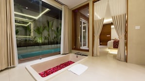 Um banheiro moderno com uma banheira grande, um box de vidro e vista para a piscina.