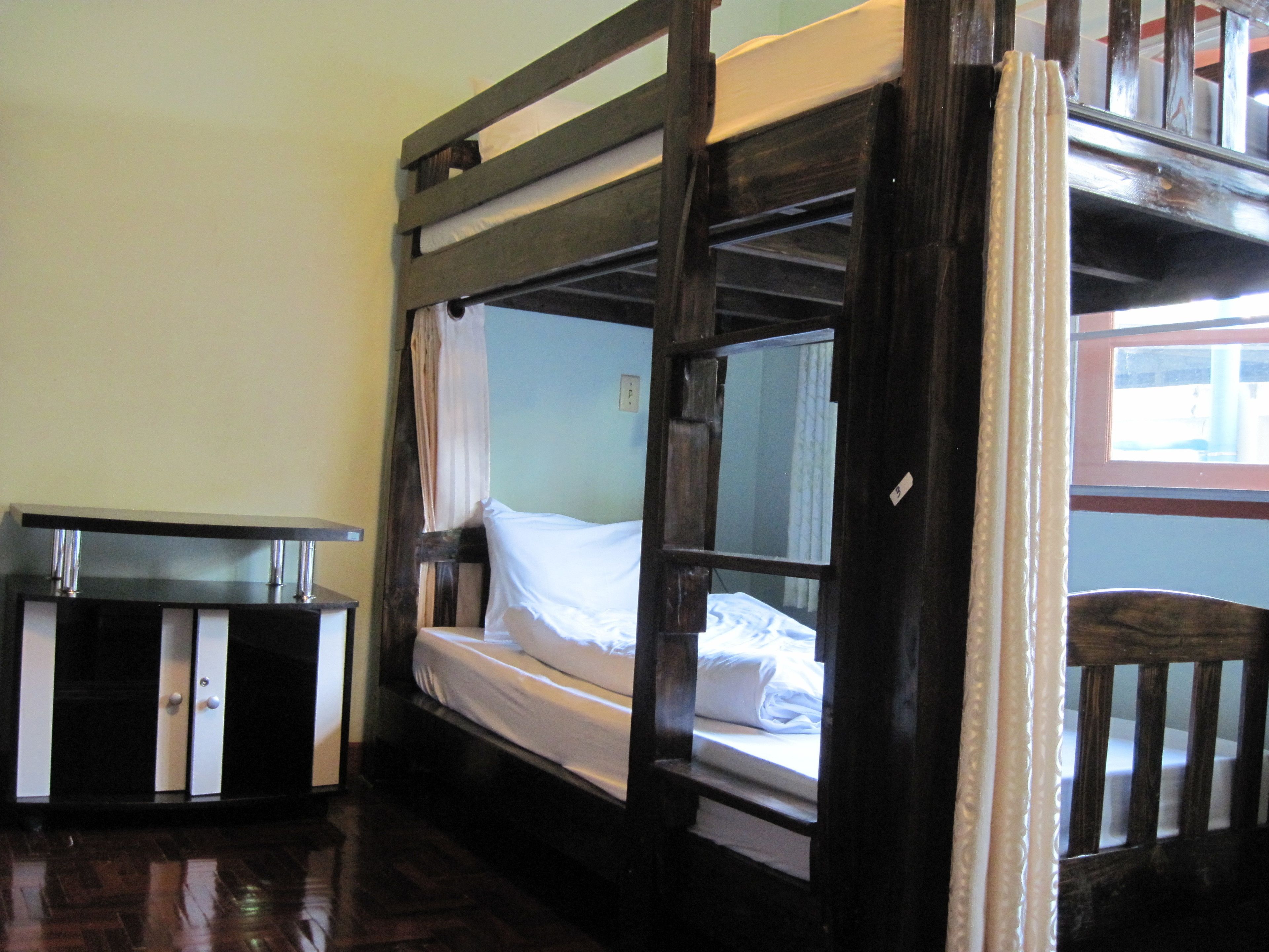 Quarto com beliche, escrivaninha de madeira e janela.