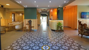 Um hall de hotel com piso estampado, móveis de madeira e um balcão de recepção.