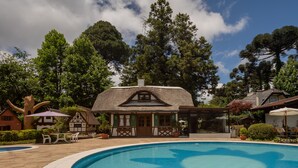Piscina com um edifício de telhado de palha ao fundo.